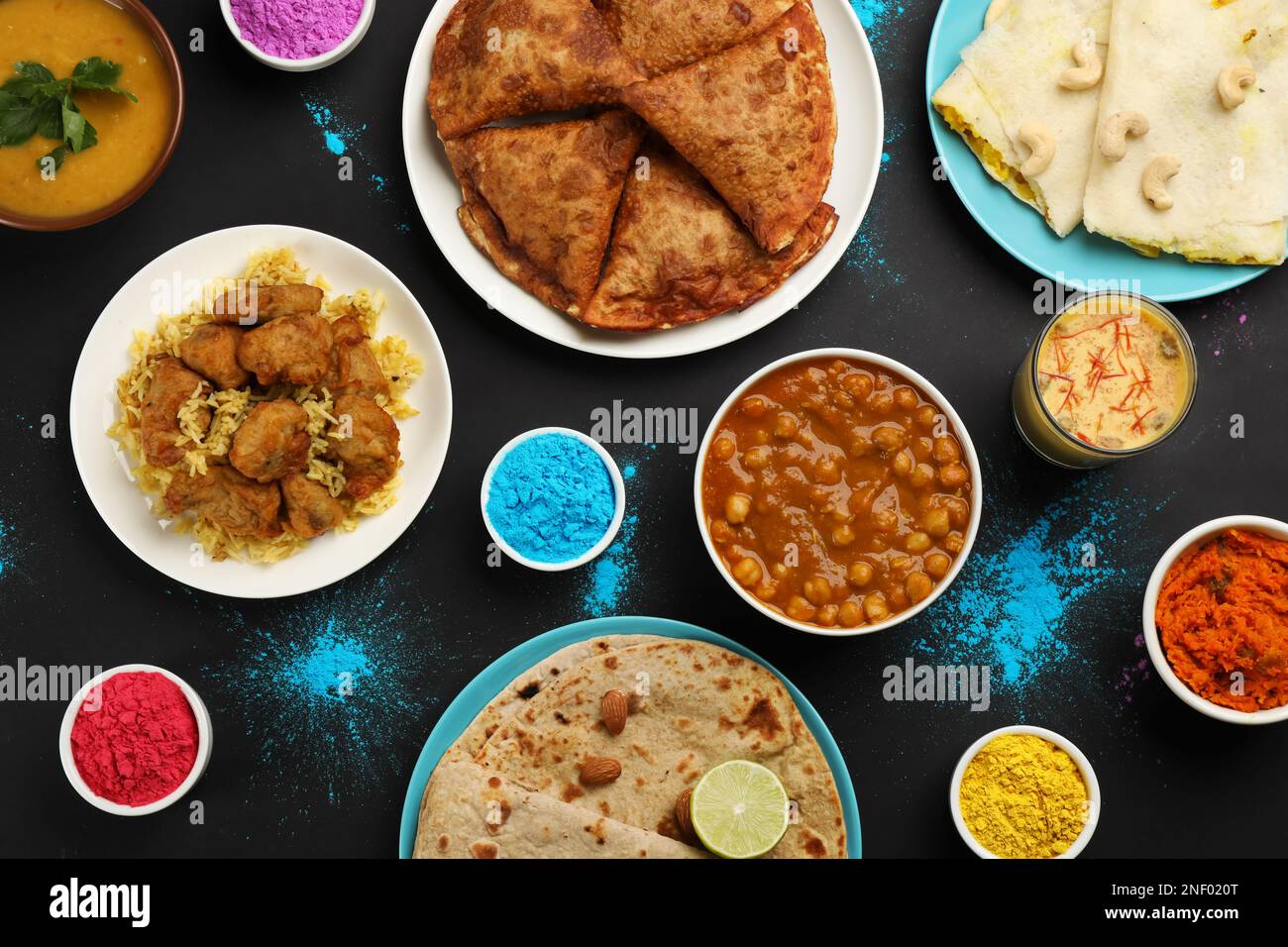Traditional Indian food and color powders on black background, flat lay ...