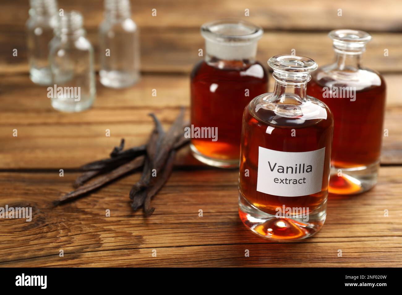 Aromatic vanilla extract and dry pods on wooden table, space for text ...