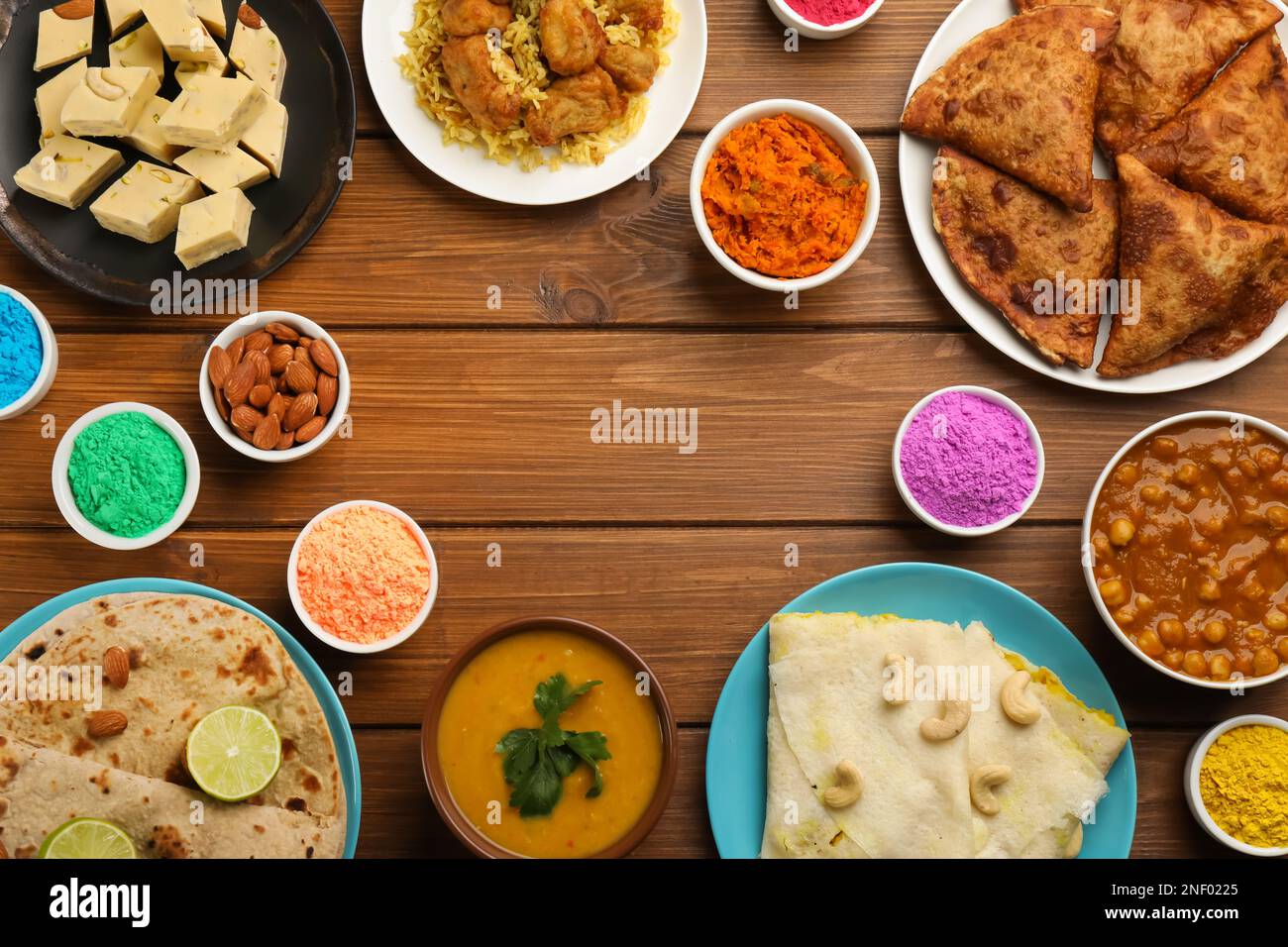 Frame of traditional Indian food and color powders on wooden table ...