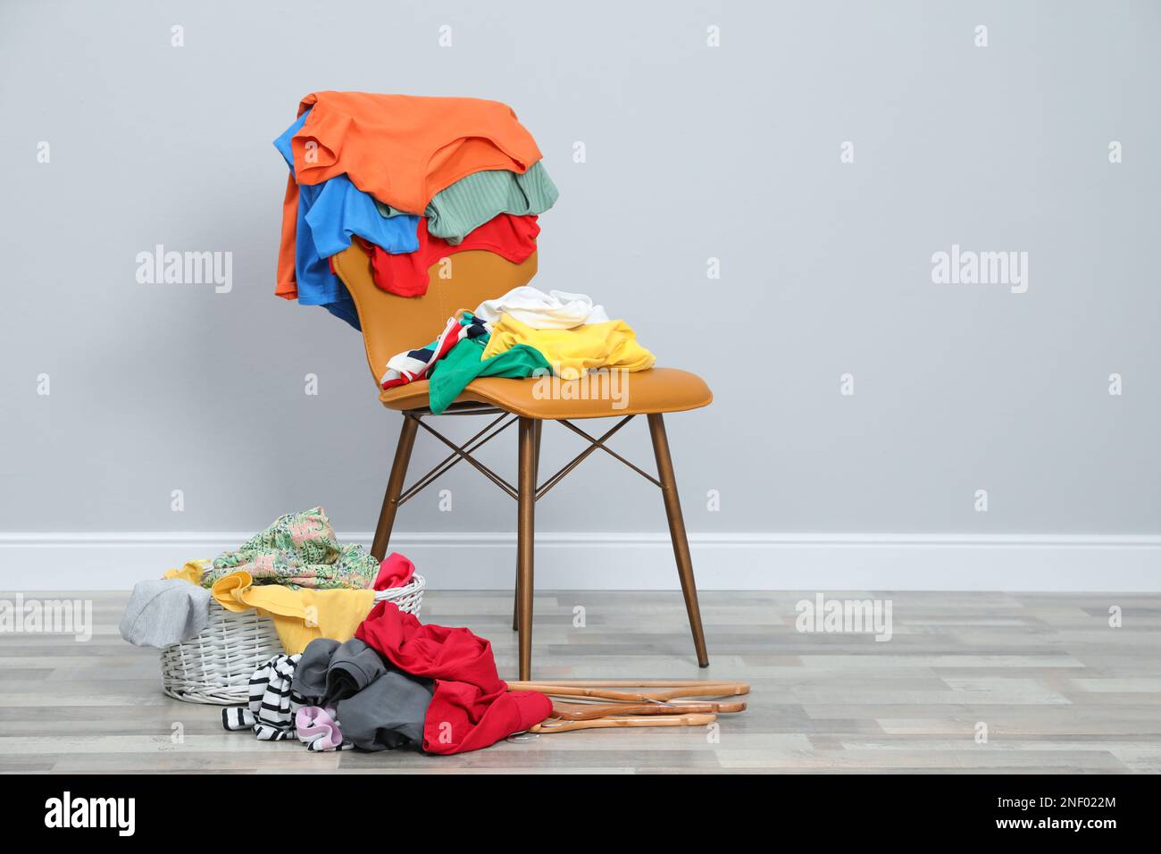 Different clothes, chair and wicker basket near grey wall Stock Photo ...