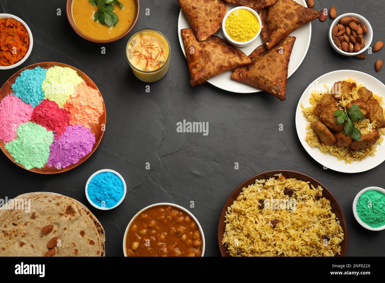 Frame of traditional Indian food and color powders on black table, flat ...