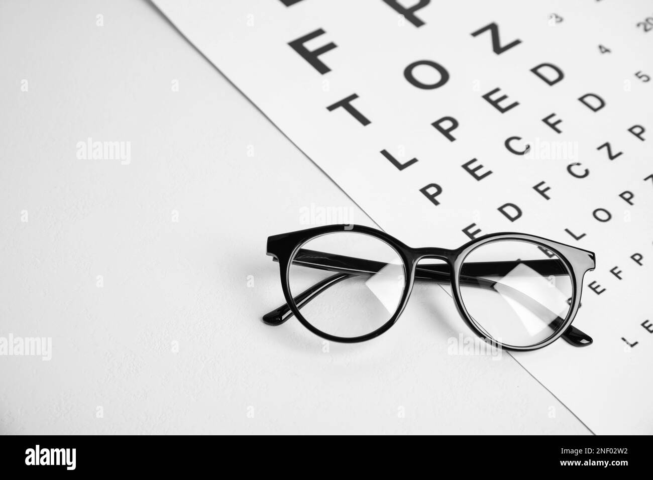 Glasses and eye chart test on white table, space for text ...