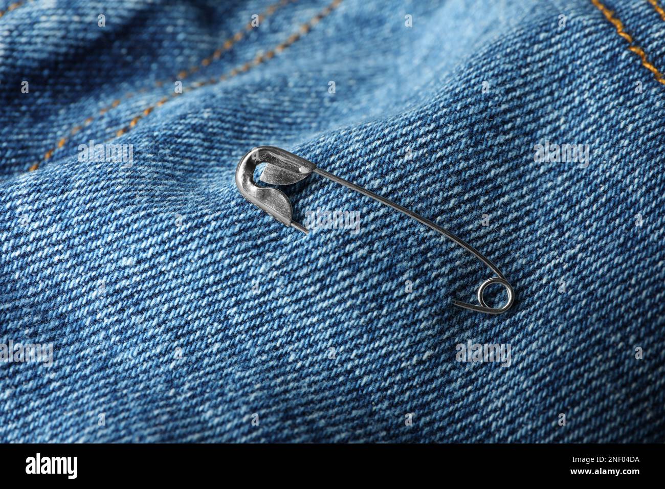 Metal safety pin on denim fabric, closeup Stock Photo - Alamy