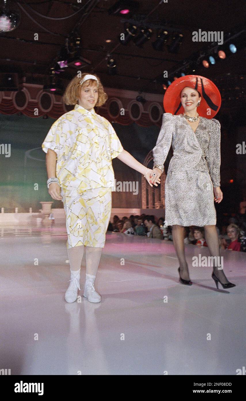 Actress Joan Collins models an ensemble as her daughter, Katy, looks on ...
