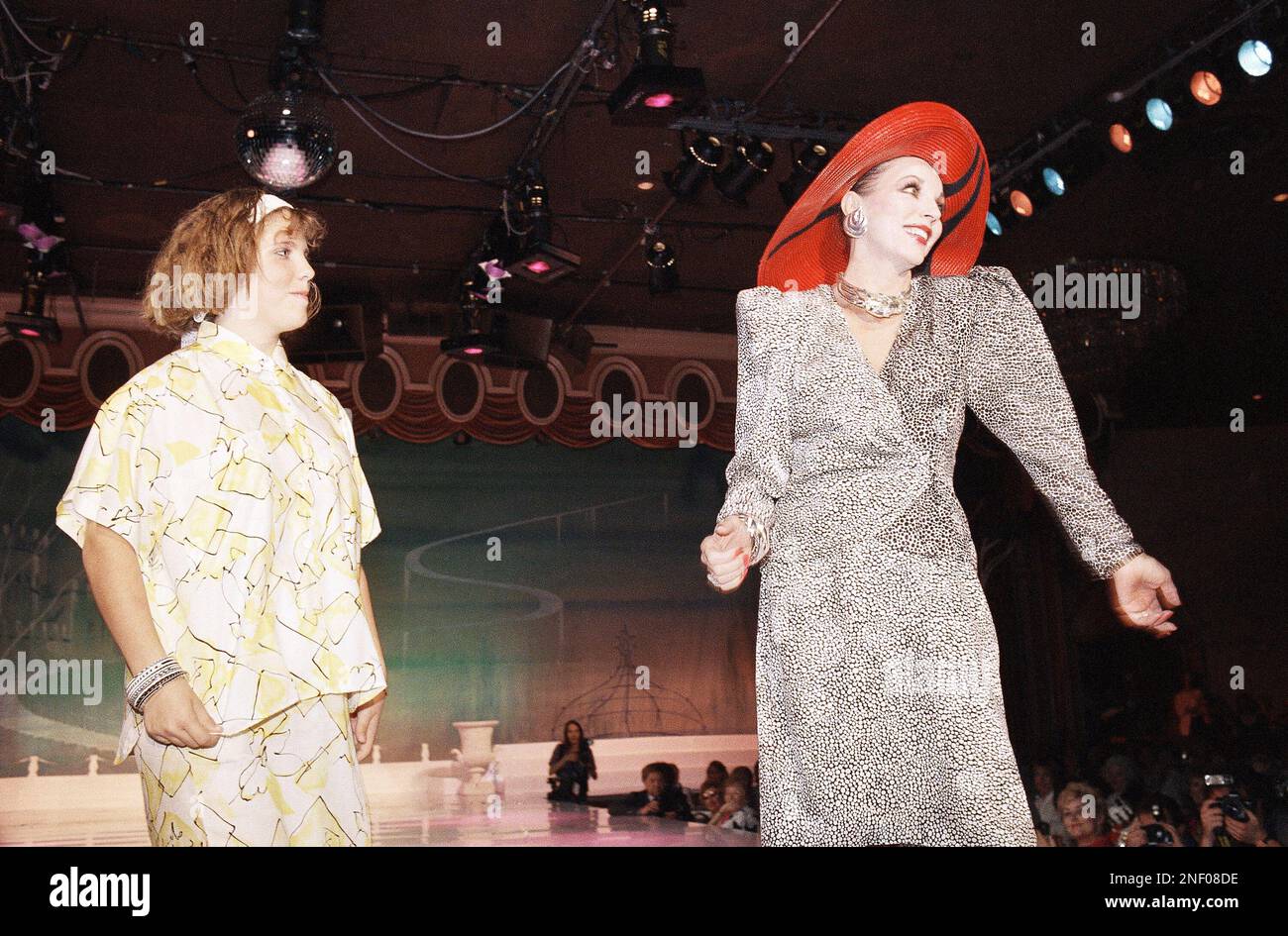 Actress Joan Collins models an ensemble as her daughter, Katy, looks on ...