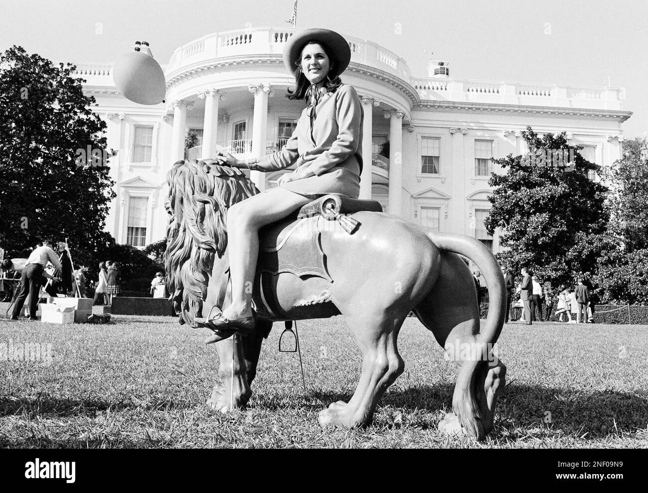 Lynda Bird Johnson hoists herself onto the back of an ornamental lion ...