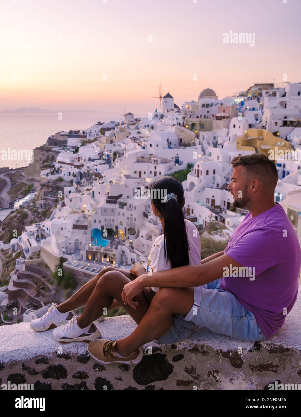 Couple watching the sunset on vacation in Santorini Greece, men and ...