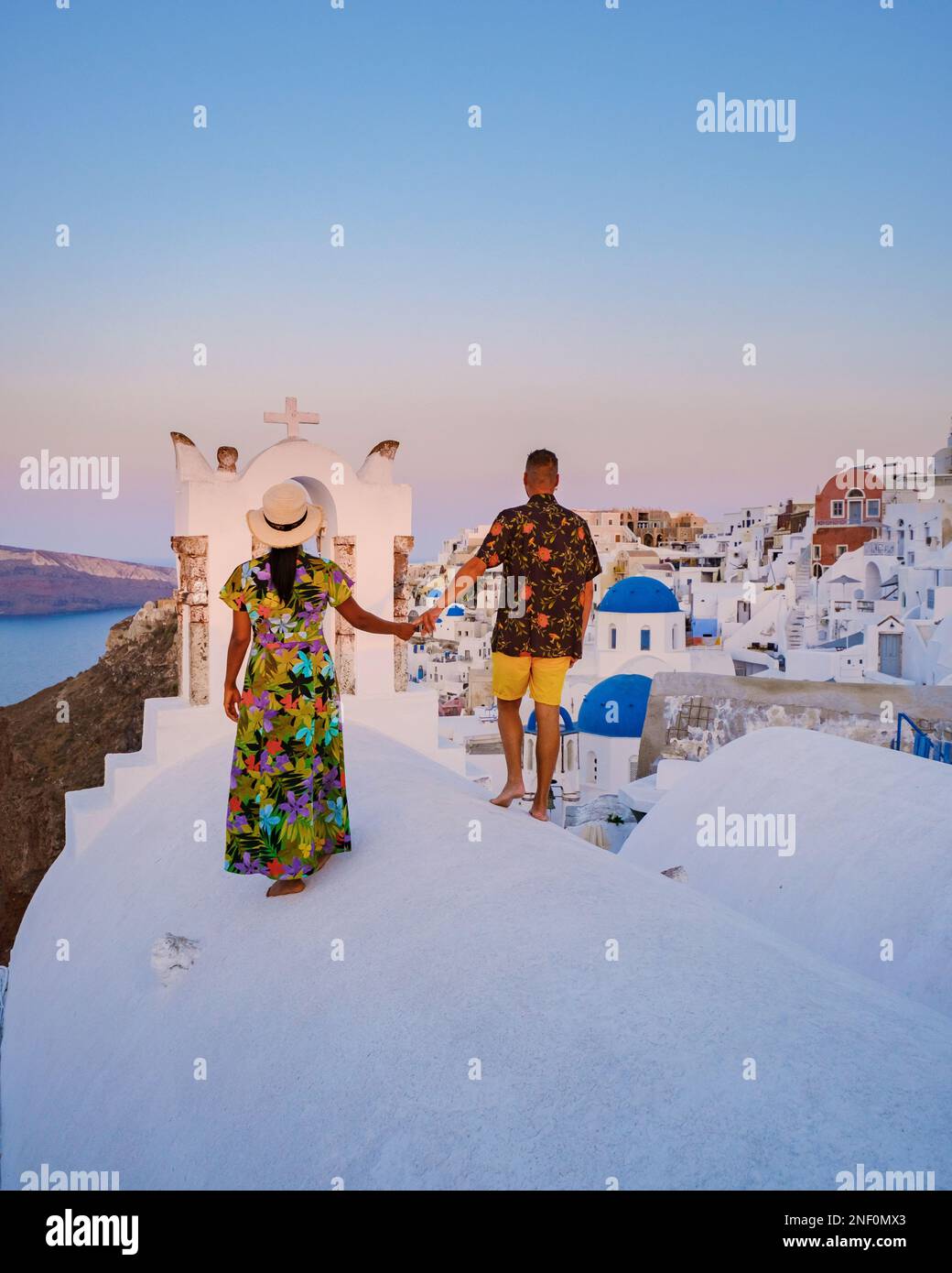 Couple watching the sunset on vacation in Santorini Greece, men and ...