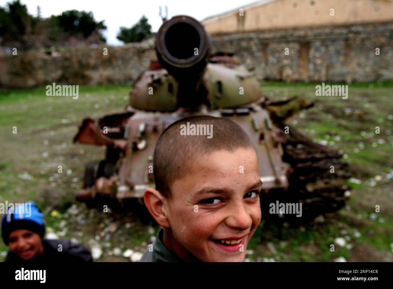 Children playing next to an abandoned tank in the outskirts of Kabul ...
