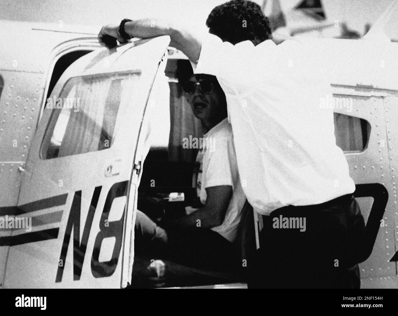 Rock Star Mick Jagger, seated, talks with an unidentified pilot before ...