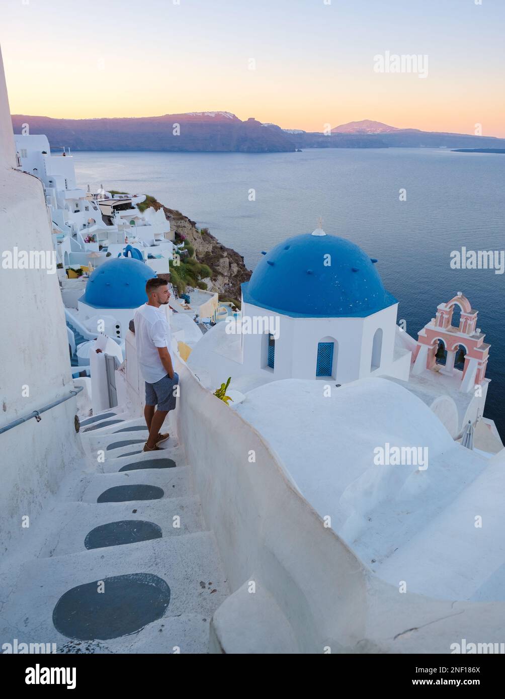 A young man on vacation in Santorini Greece, men visit the whitewashed ...