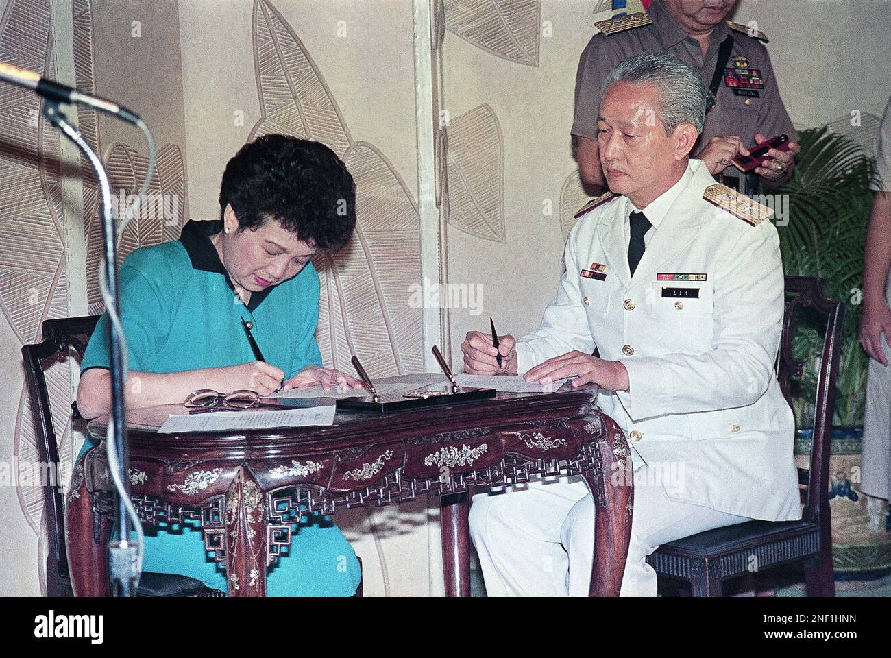 Philippine President Corazon Aquino, left, signs document in front of ...