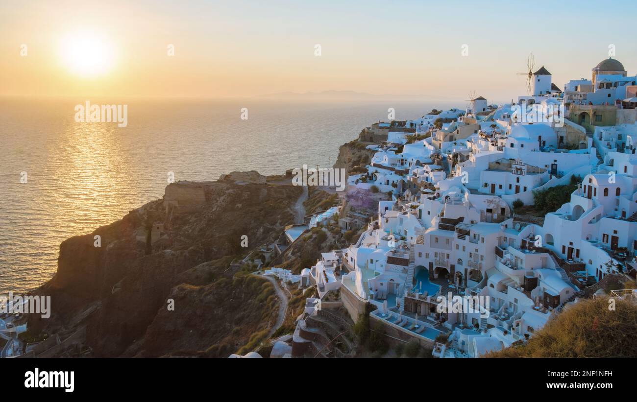 sunset with white churches an blue domes by the ocean of Oia Santorini ...