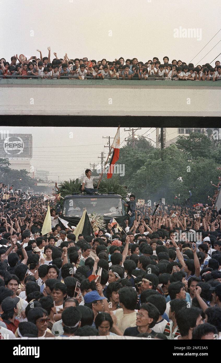 Thousands of Filipinos block the road and climb on the hearse carrying ...