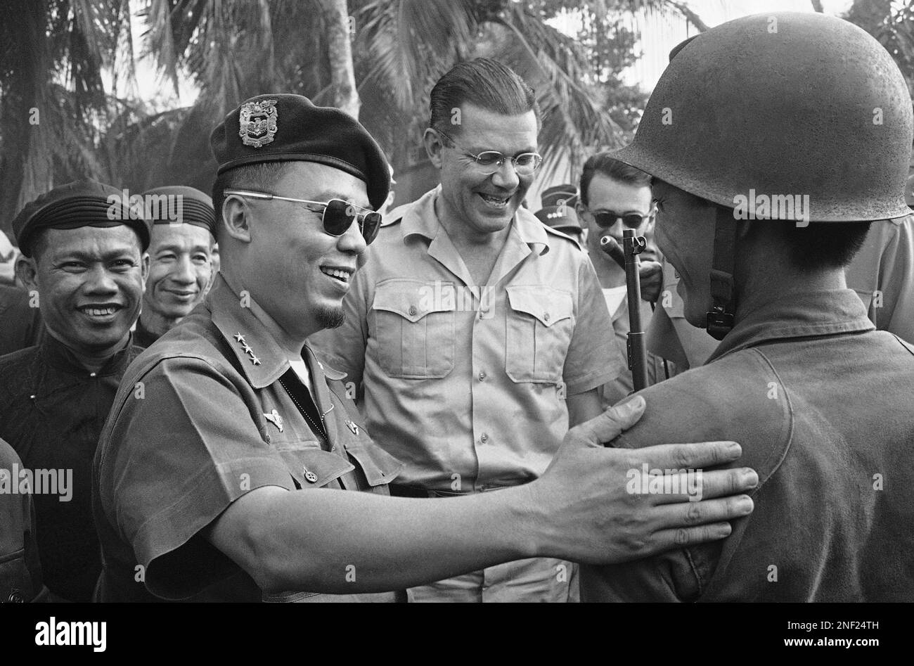 U.S. Secretary of Defense Robert S. McNamara, center, stands beside ...