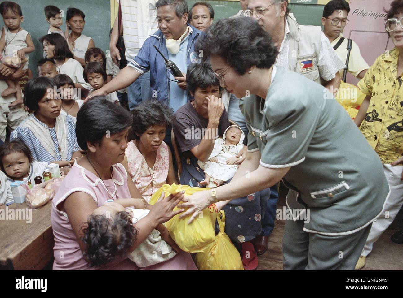 Philippine President Corazon Aquino hands food and relief supplies to ...