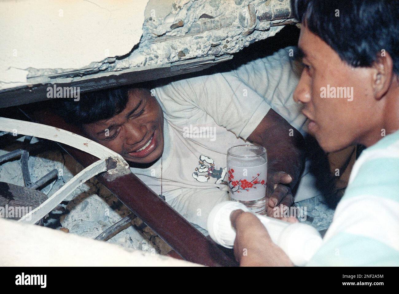 A rescuer passes a cup of water to one of scores of people believed ...