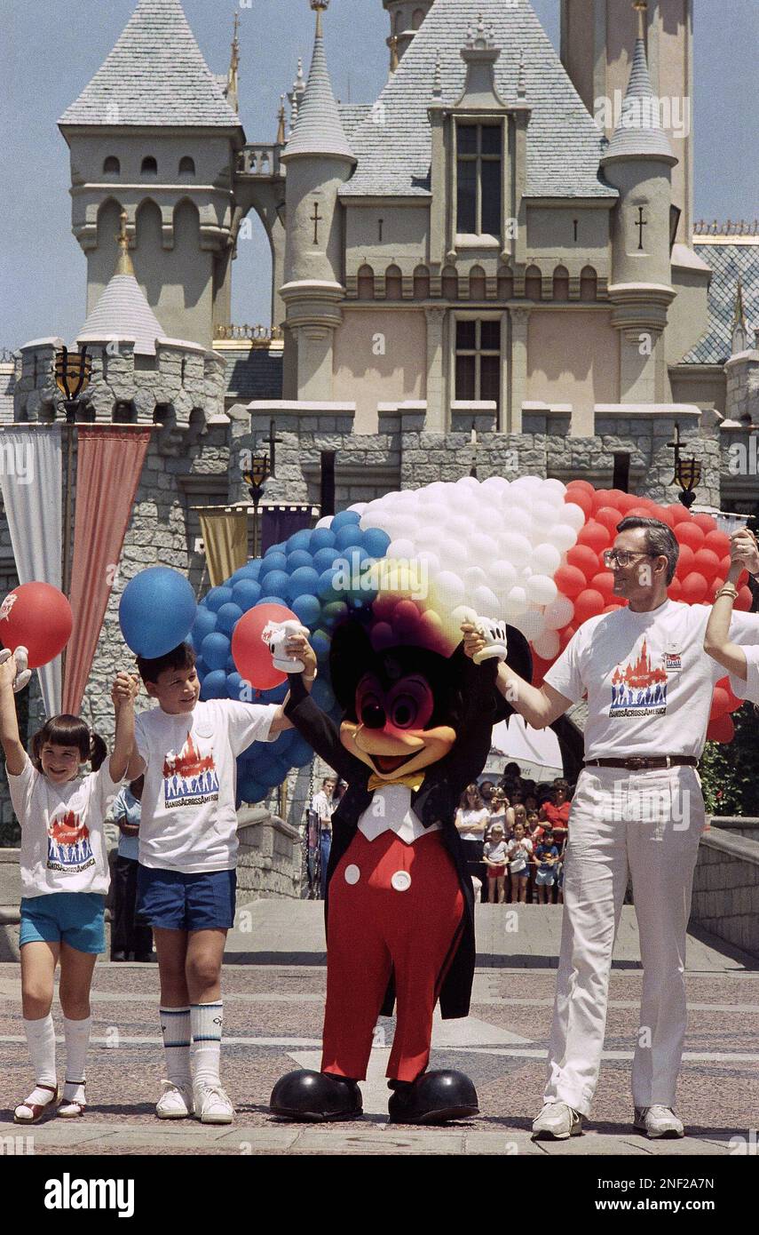 Mickey Mouse, center, holds hands with 10-year-old Kirk Aquiar, left ...