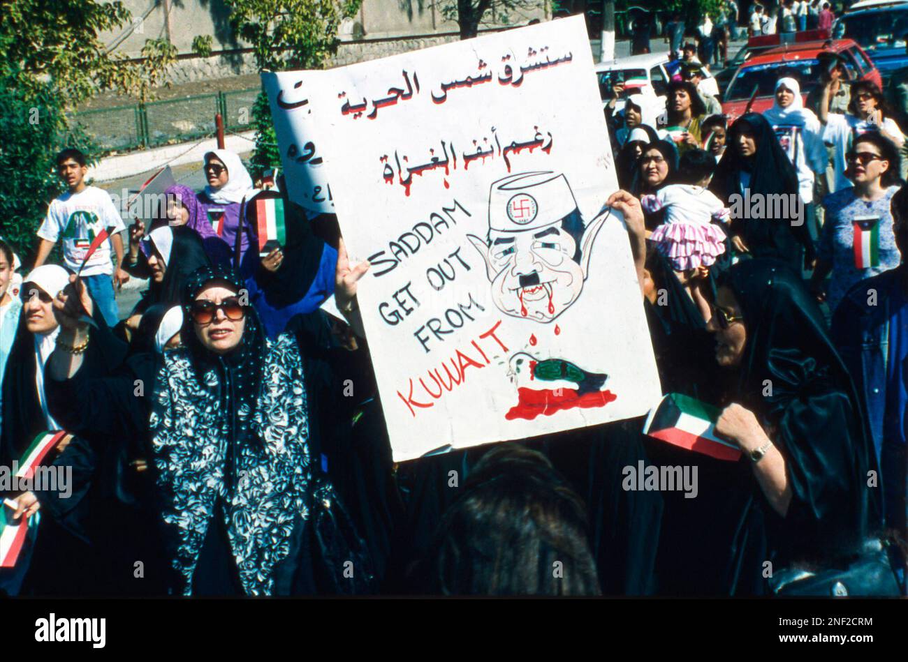 8-Two Kuwaiti demonstrators holding placard which shows Saddam Hussein ...