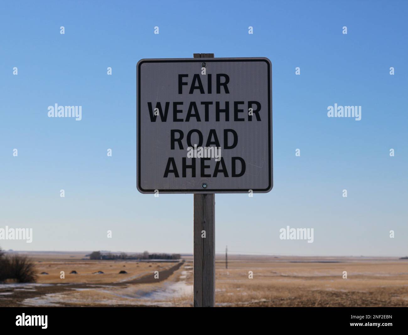 A fair weather road ahead sign along a dirt road in Canada with ...