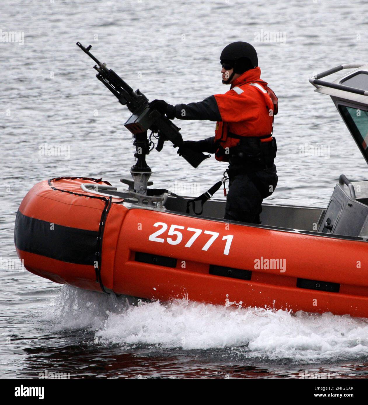 A U.S. Coast Guard boat, with a manned mounted gun at the front ...