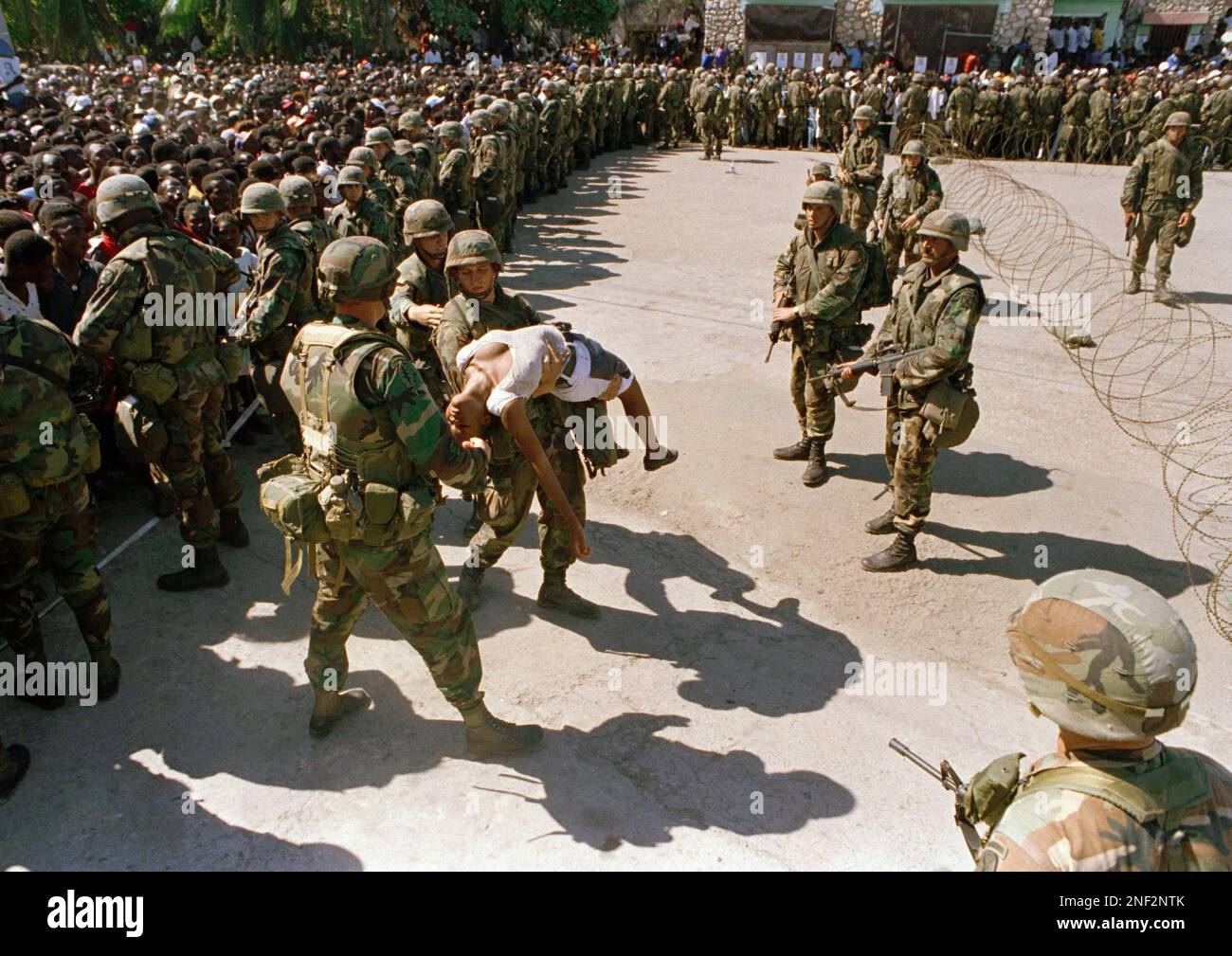 U.S. soldiers carry off a Haitian woman who fainted in a crowd of ...
