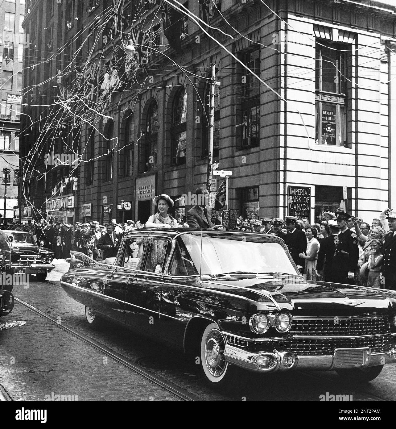Queen Elizabeth II and Prince Philip stand in their open Cadillac ...