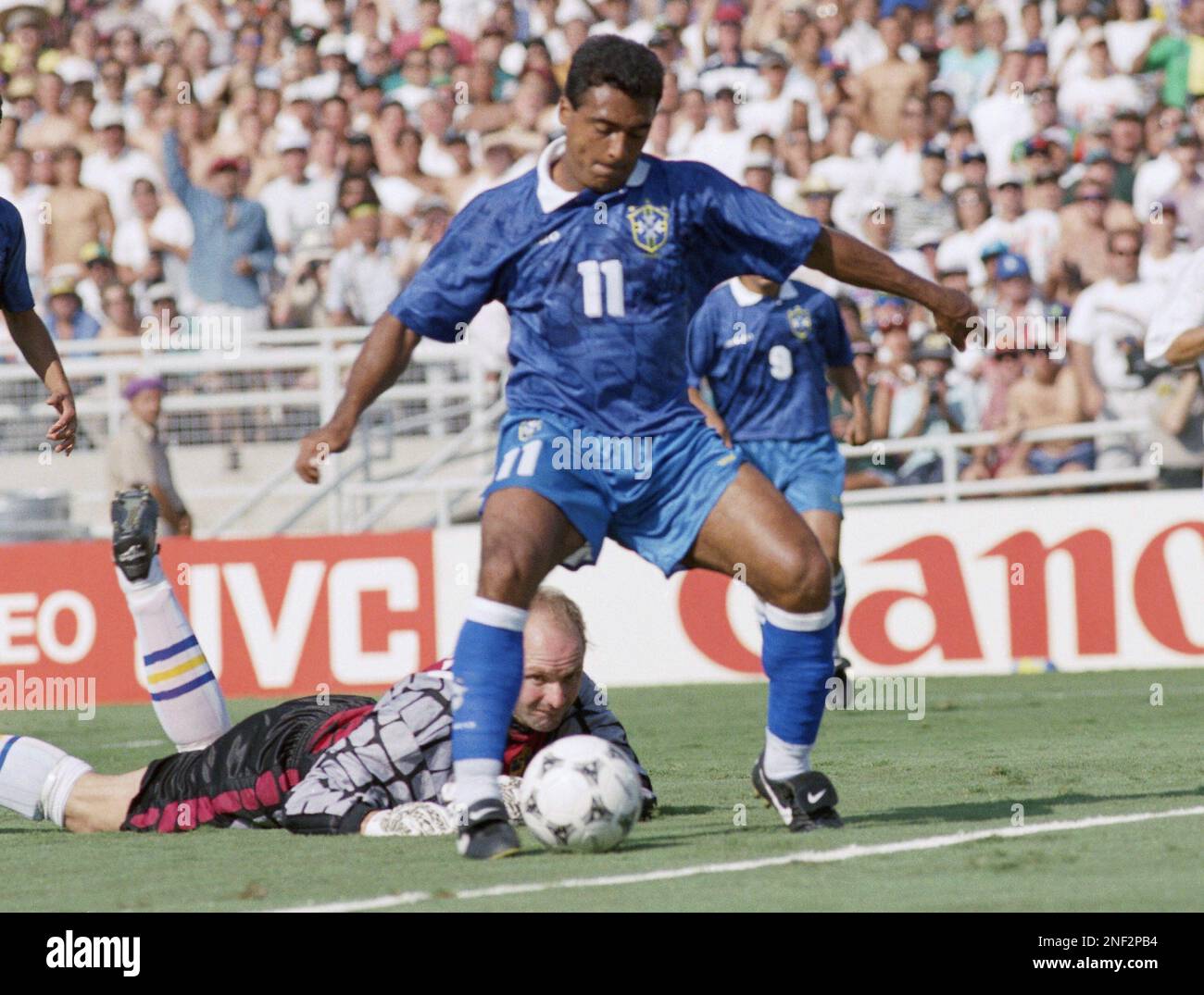 Swedish goalie Thomas Ravelli watches Brazilian forward Romario dribble ...