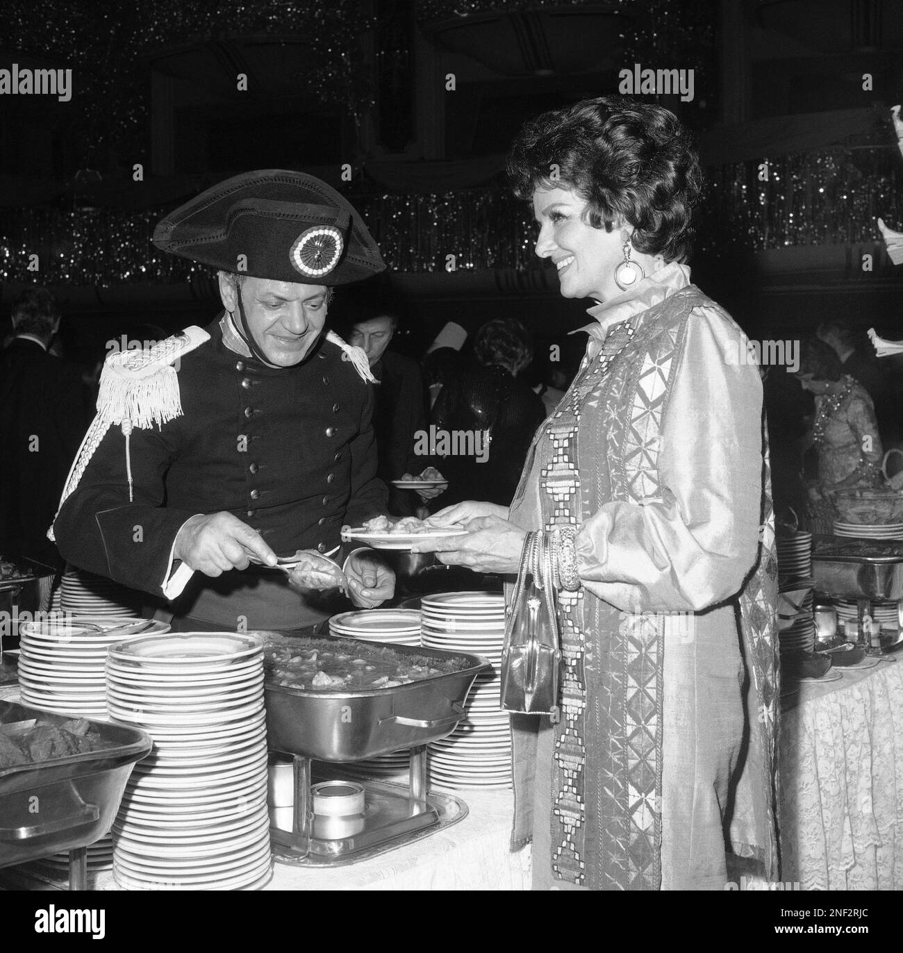 Actress Jane Russell is served her dinner by an unidentified costumed ...
