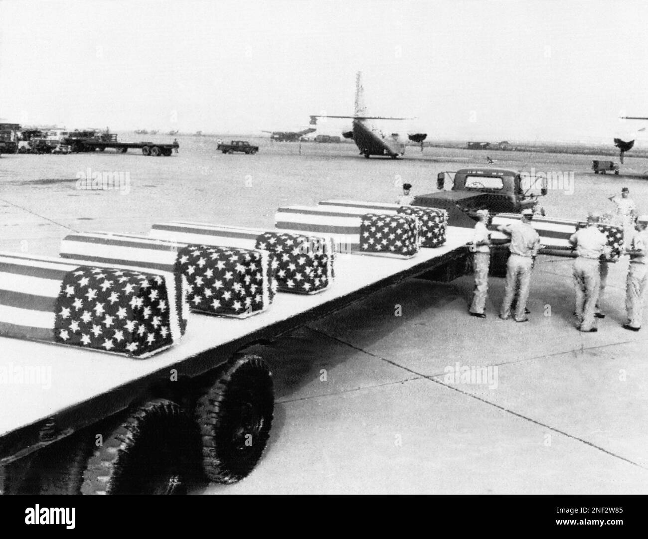 U.S. Servicemen lift one of the six-flag covered caskets of comrades ...