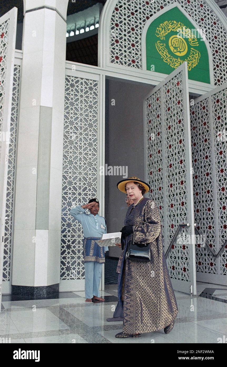 An attendant at the Sultan Salahuddin Abdul Aziz Shah Mosque salutes ...