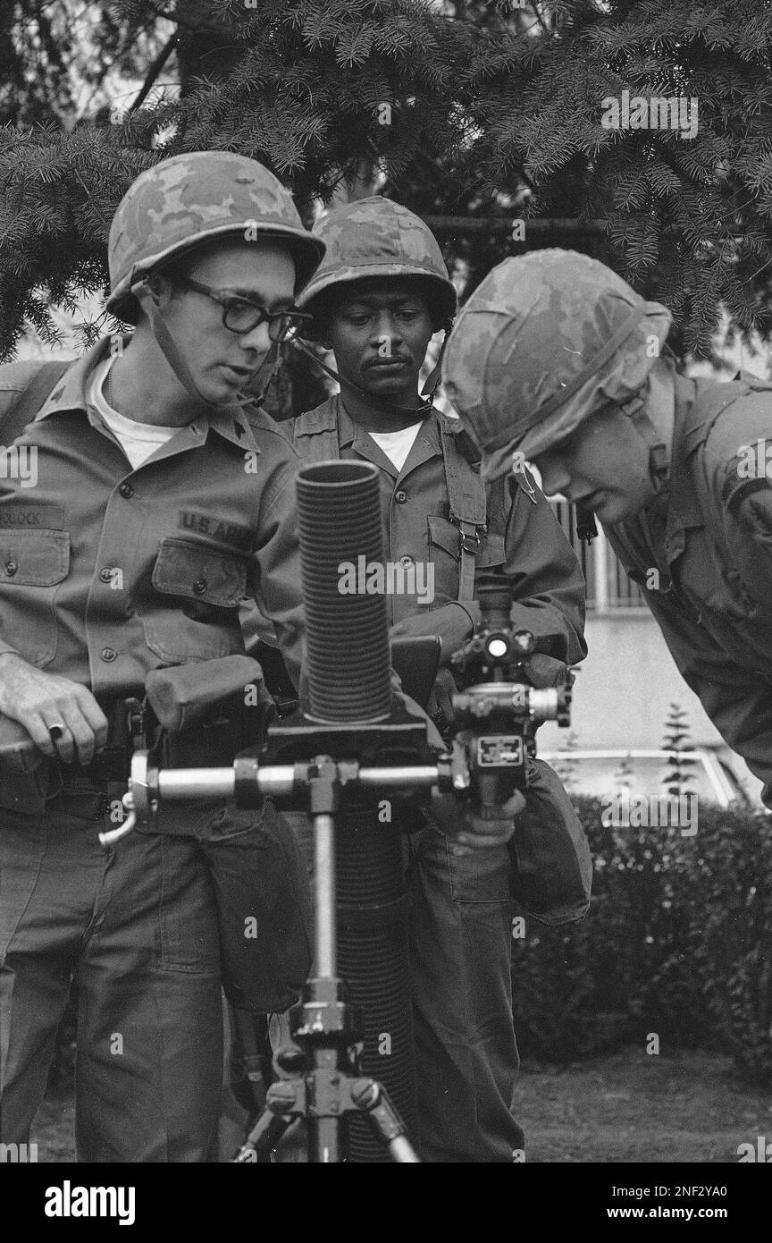 Black and white soldiers work together during a drill with a mortar ...