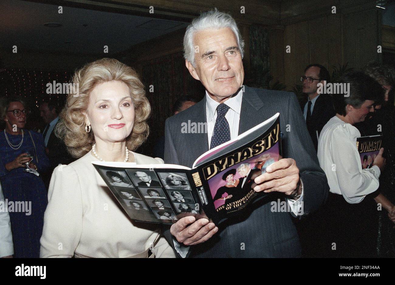Actor John Forsythe and his wife Julie looking at a book about "Dynasty ...