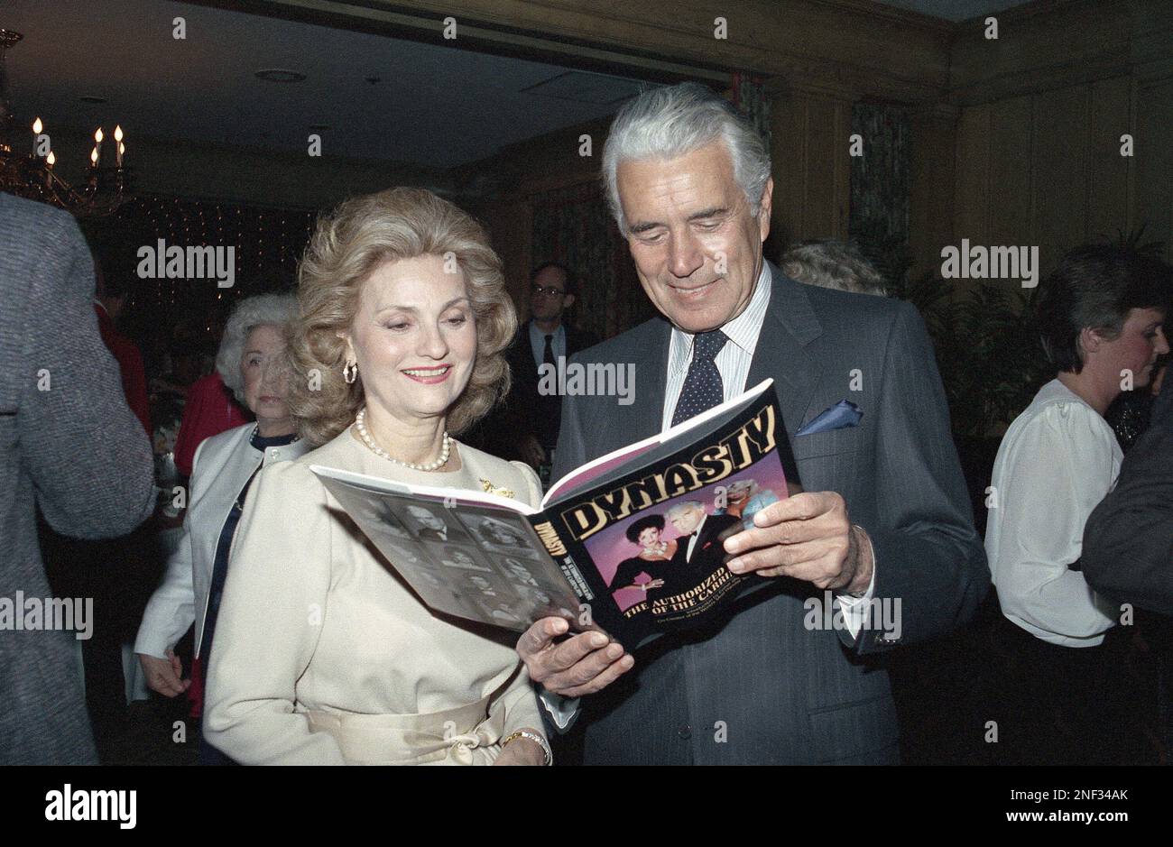 Actor John Forsythe and his wife Julie looking at a book about "Dynasty ...