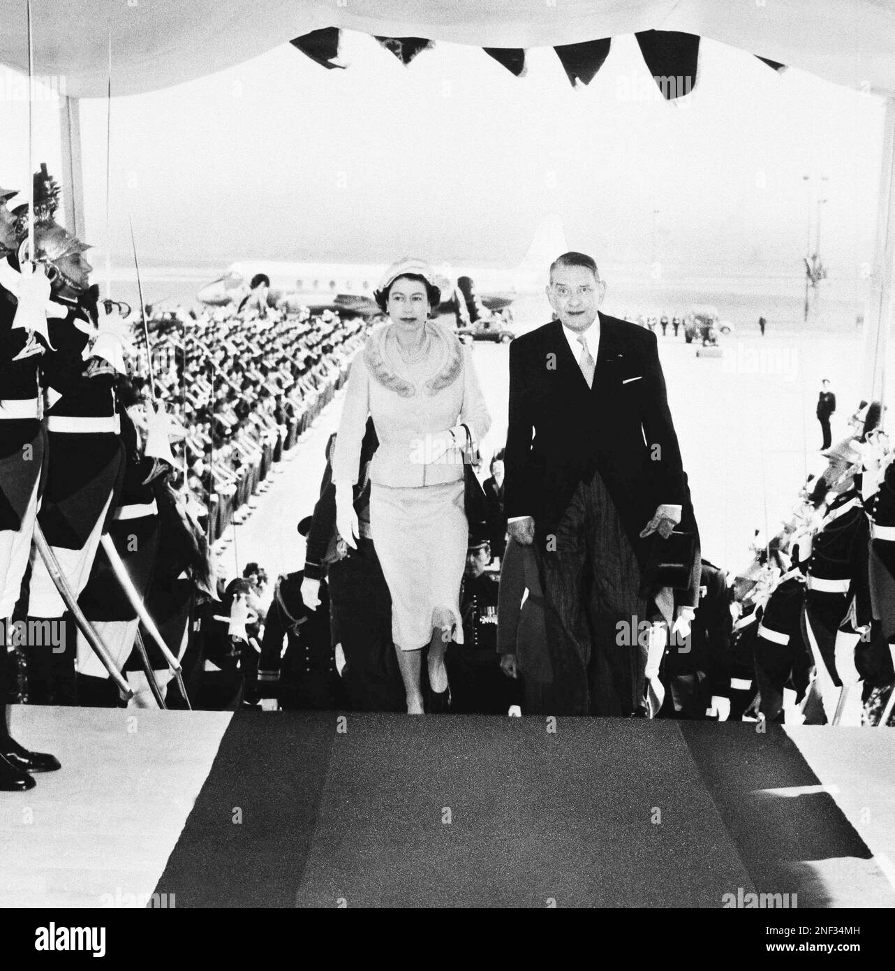 Queen Elizabeth II of England wears a slim skirted suit as she is ...