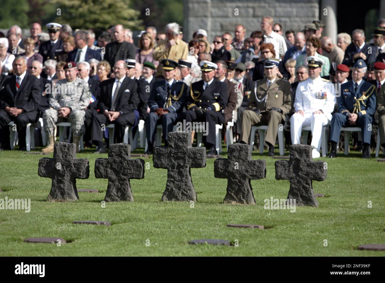 Officials sit behind the World War II graves of German soldiers during ...