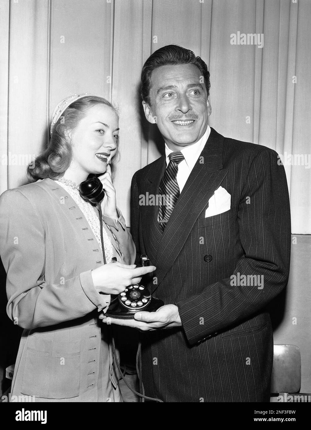 Leon Ames holds the phone for Audrey Totter while she puts in a call ...
