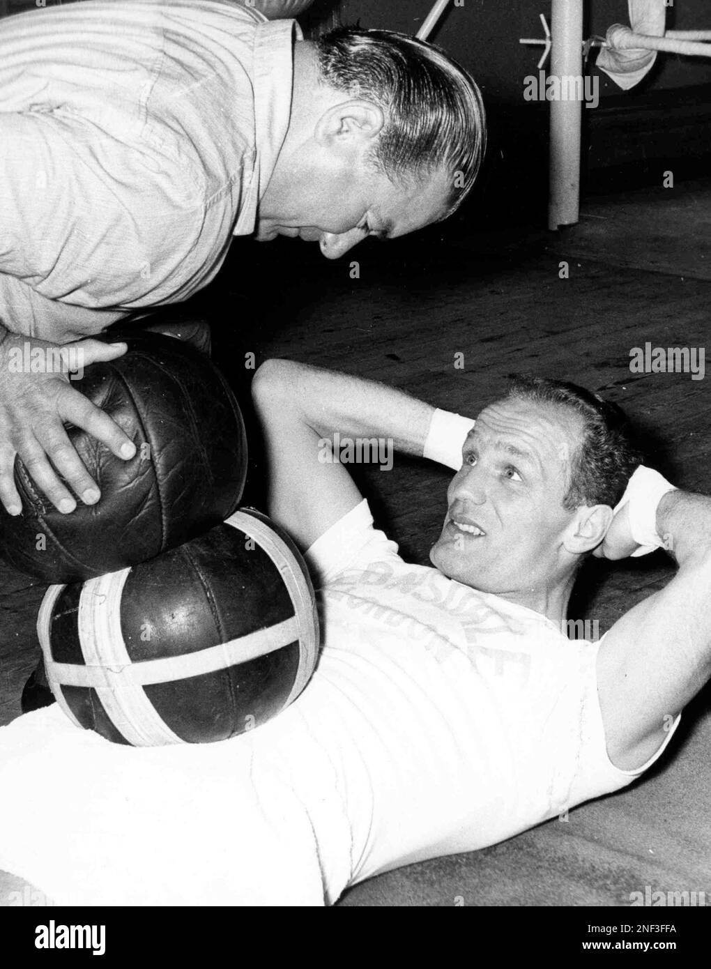 British heavyweight boxer Henry Cooper has two heavy medicine balls ...