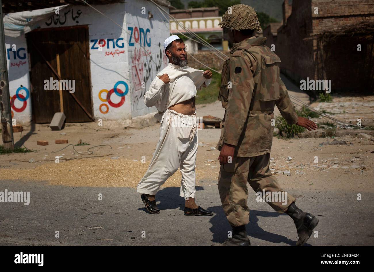 In this May 27, 2009 image, a Pakistani displaced man rises his clothes ...