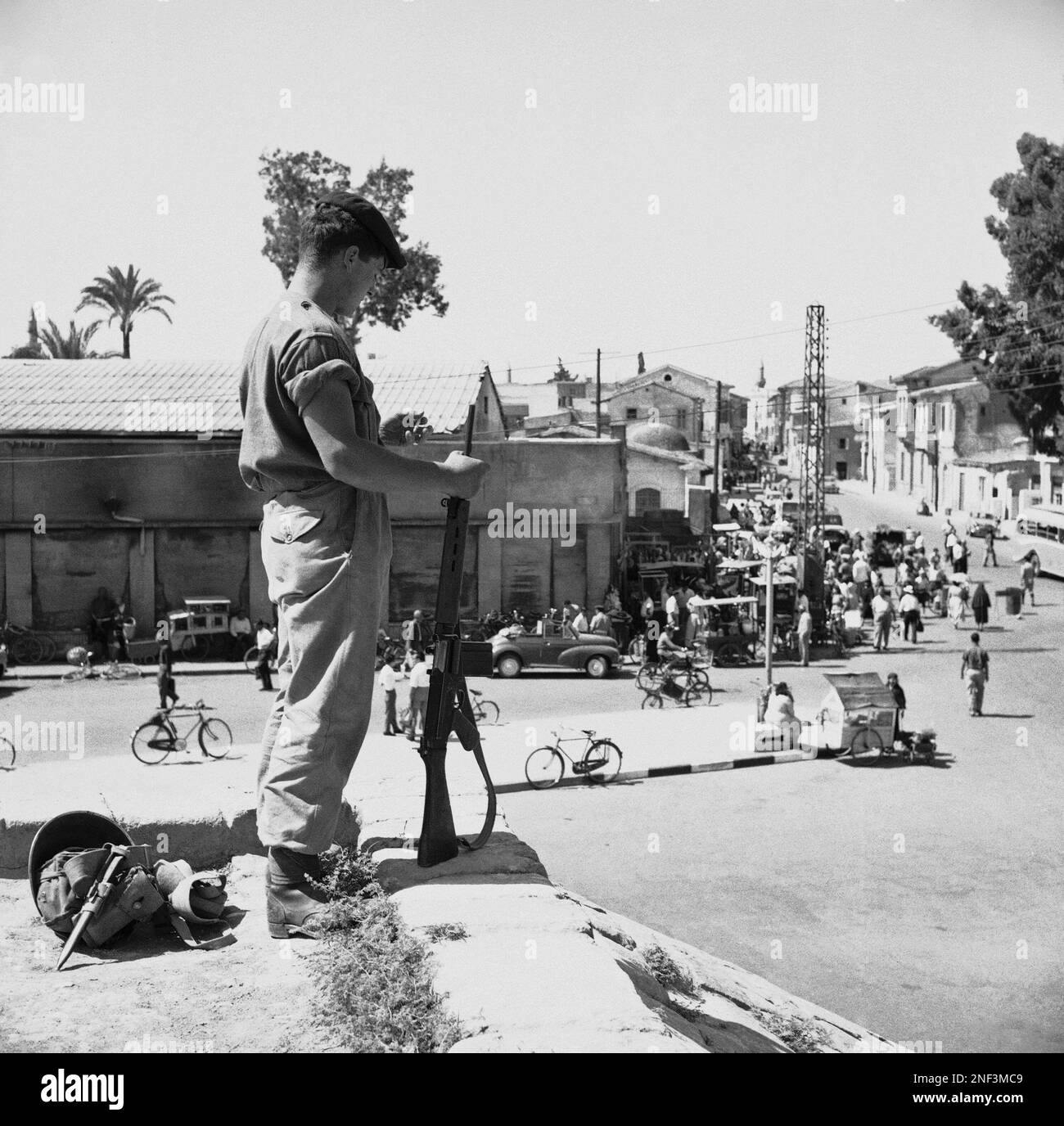 Armed with a rifle, a British soldier stands guard atop a wall ...