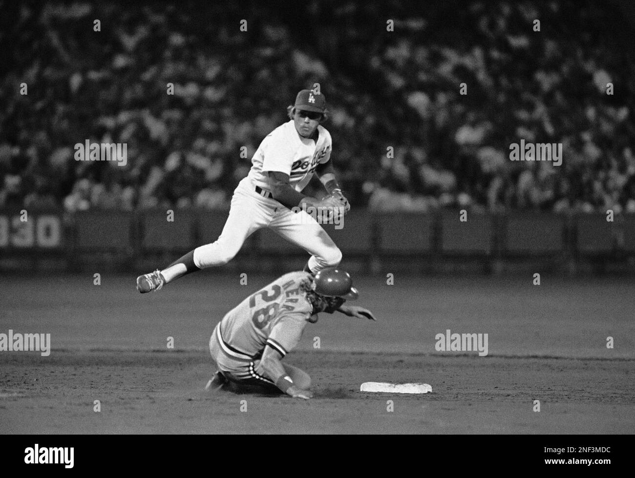 Dodger shortstop Bill Russell leaps over the sliding Tom Herr of the St ...
