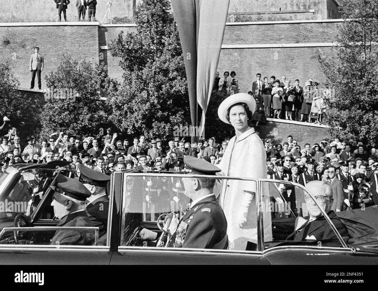Queen Elizabeth II stands in an open limousine on her way from Rome's ...