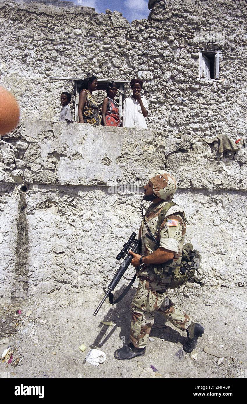 A U.S. marine is watched by some Somalis as he patrols through ...