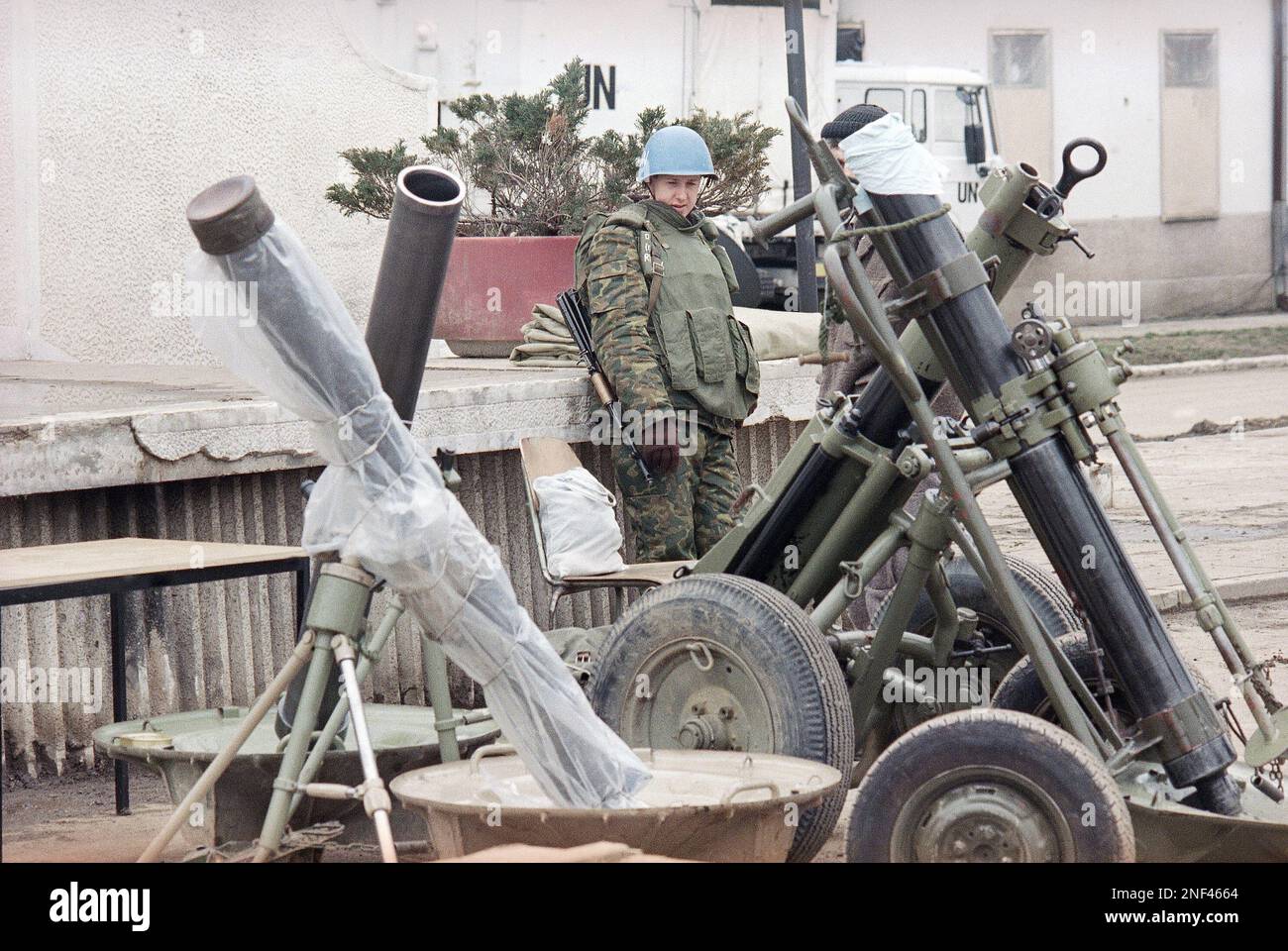 An Ukrainian U.N. peacekeeper stands guard behind four 120 mm mortars ...