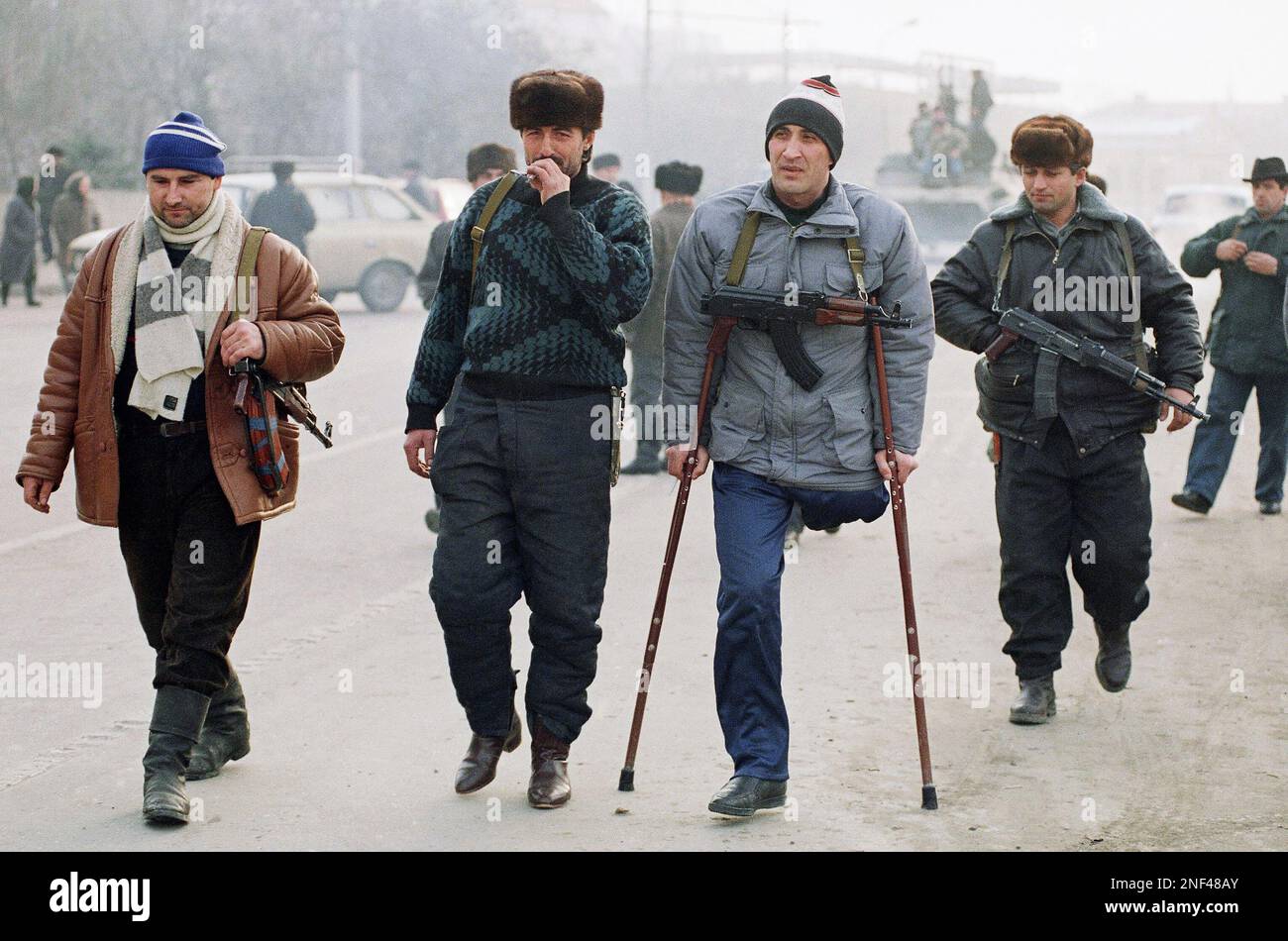 Chechen armed volunteers, one an amputee on crutches, walk to their ...