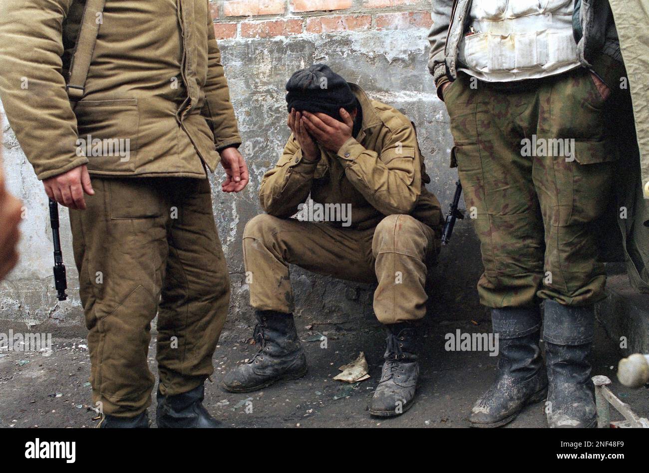 A Chechen fighter hangs his head in his hands, mouring the loss of a ...