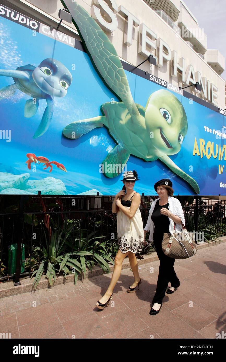 Festival goers walk past a poster advertising the animated movie ...