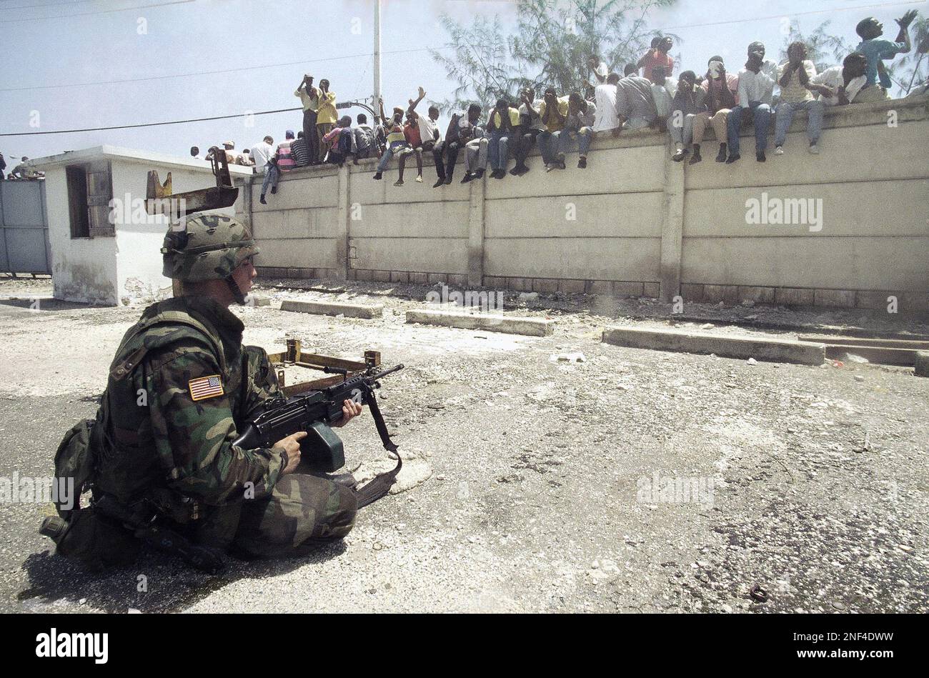 A U.S. Army soldier watches Haitians as they watch him from a wall ...