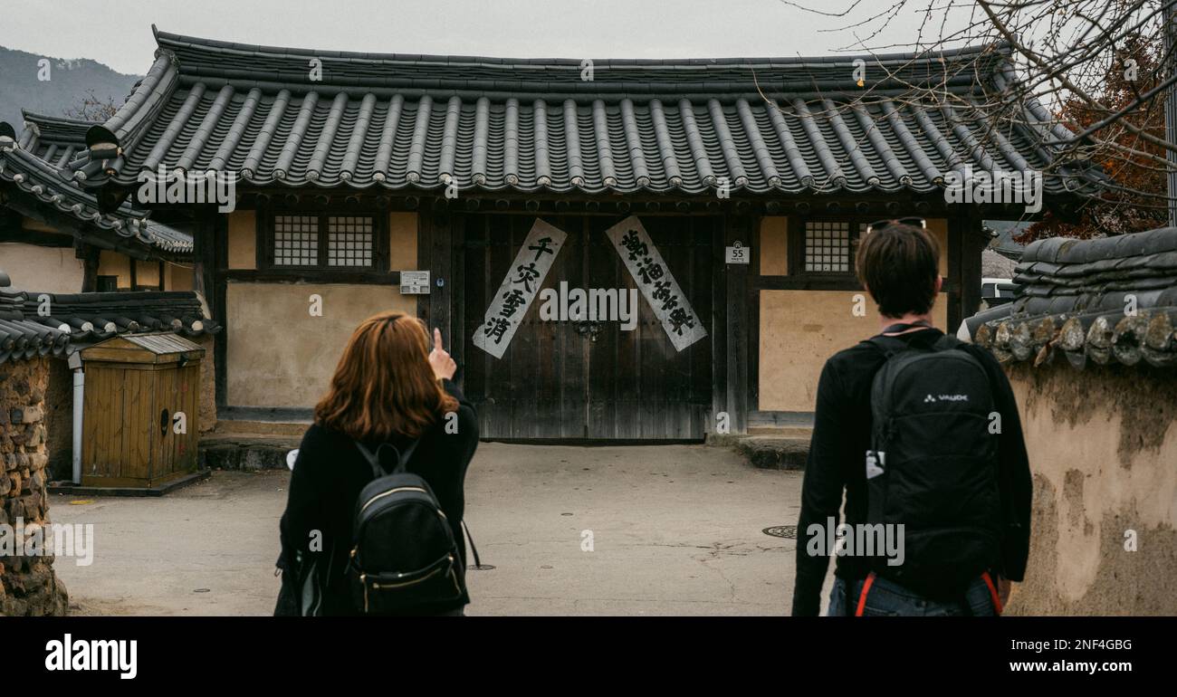 A male and a female explore a Korean temple at Hahoe Folk Village on an overcast day in Andong ...