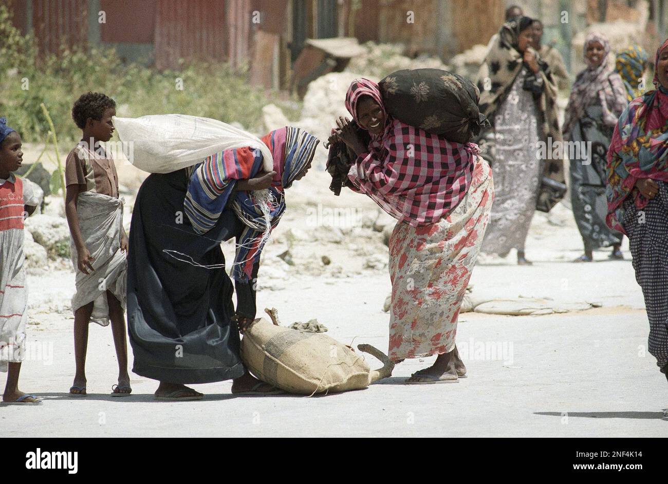 Two Somali women struggle with their belongings as they pass through ...